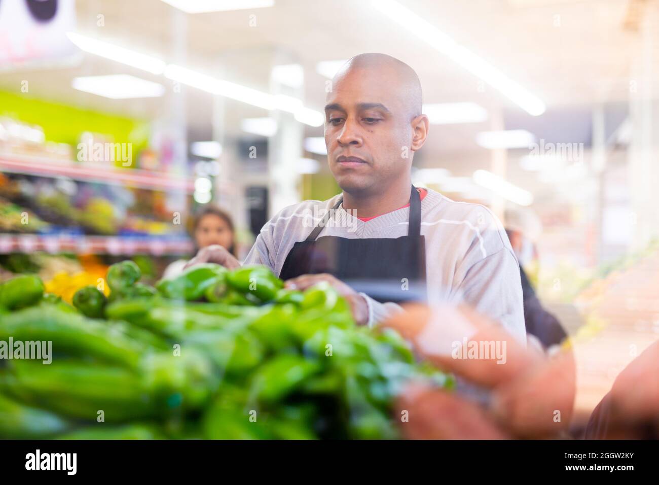 Man working in supermarket near vegetable section Stock Photo - Alamy