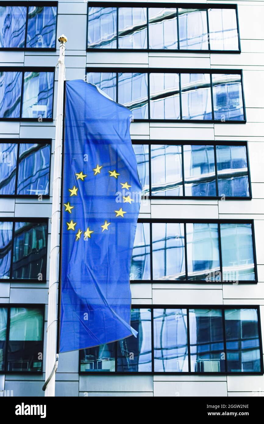 European Union flag waving in front of modern corporate office building ...