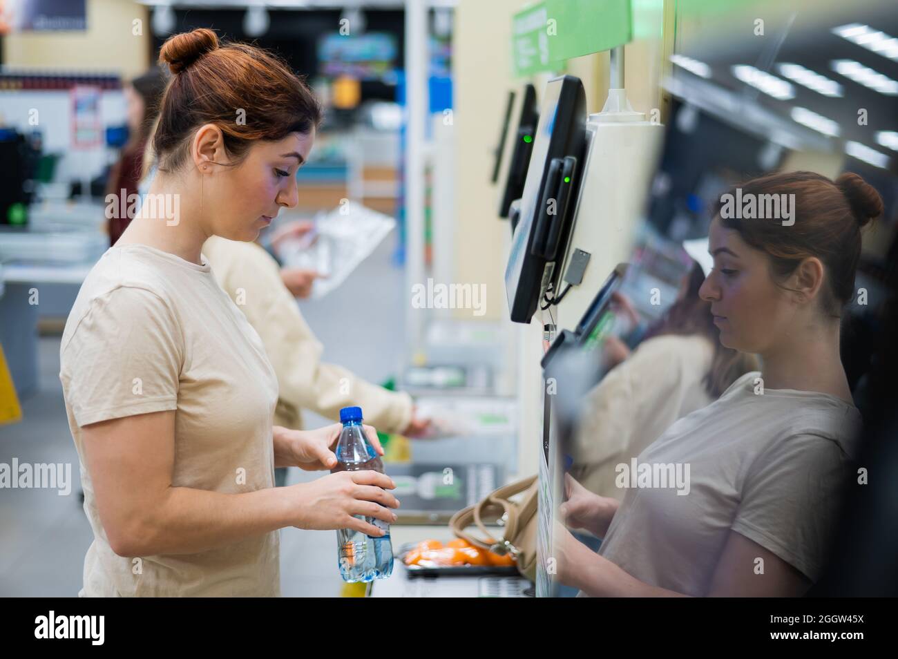 A frustrated woman uses a self-checkout counter. The girl does not ...