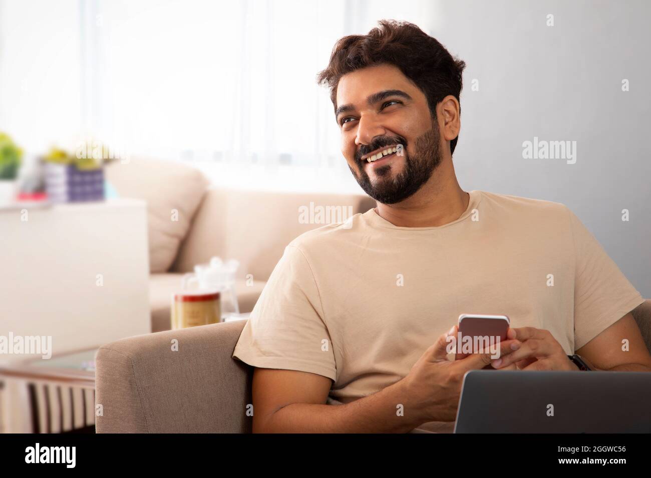 A man sitting with laptop holding his mobile looking sideways Stock ...