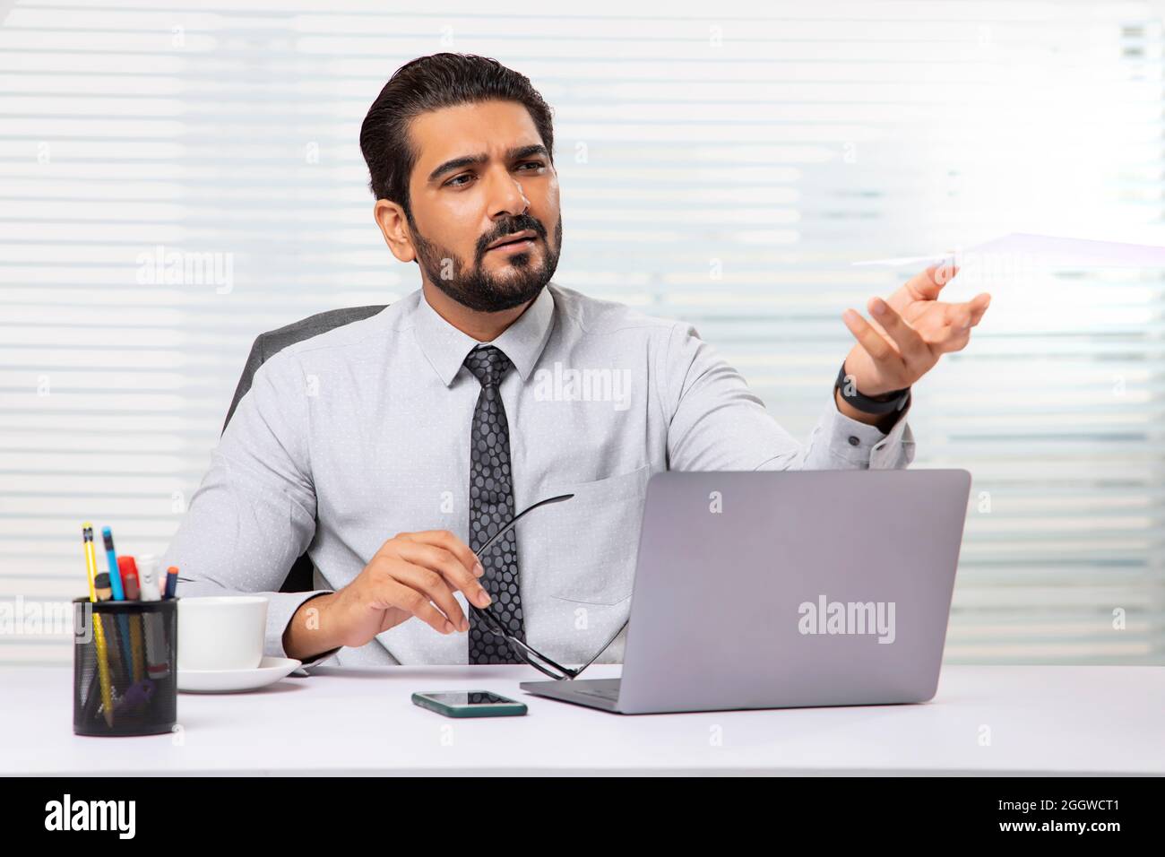 An employee sitting in office giving a paper from his hand Stock Photo ...