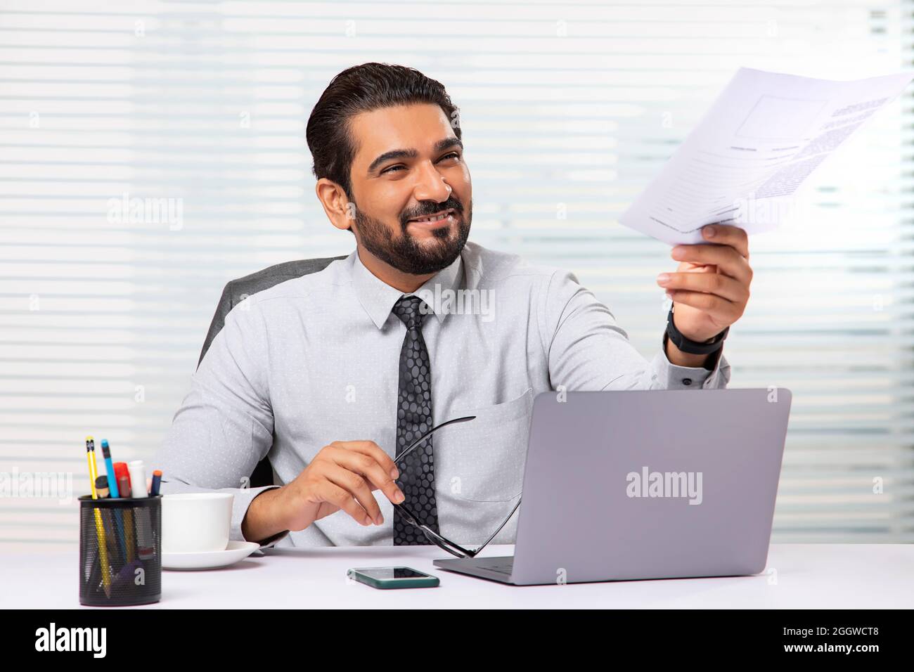 An employee sitting in office giving a paper from his hand Stock Photo ...