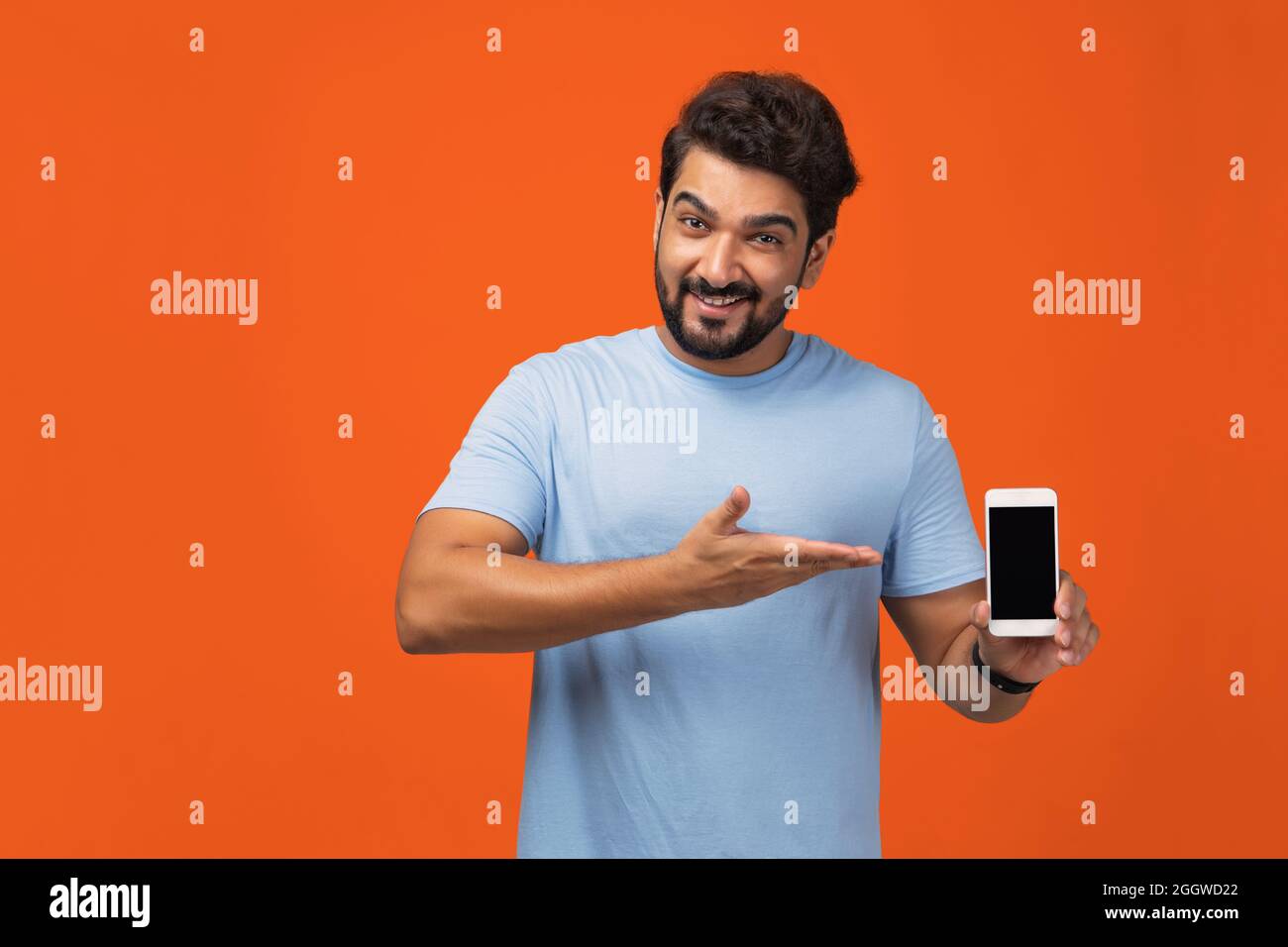Portrait of a man showing mobile phone in his hand against plain ...