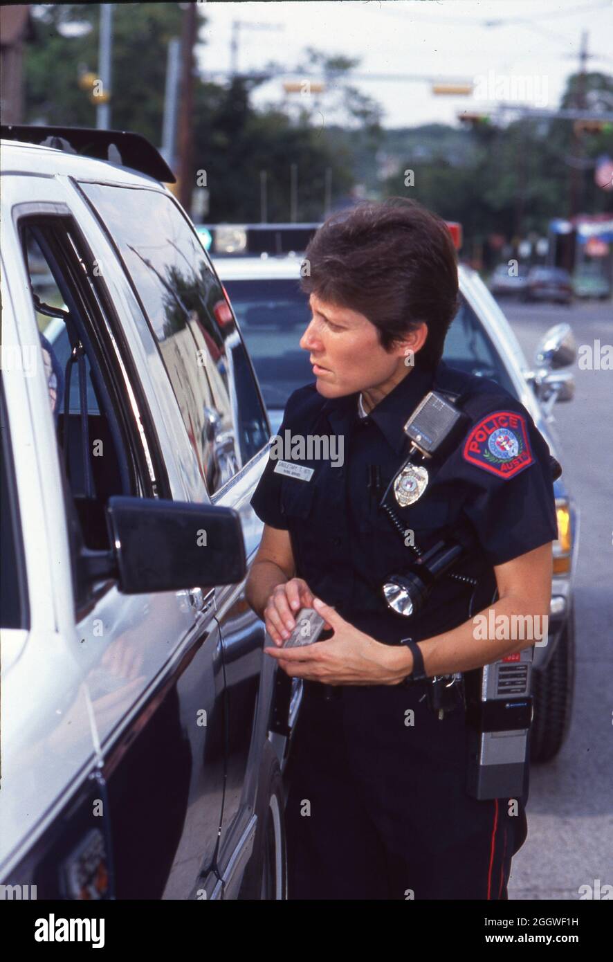 ©1991 Hispanic female police officer on duty, checking licenses on ...
