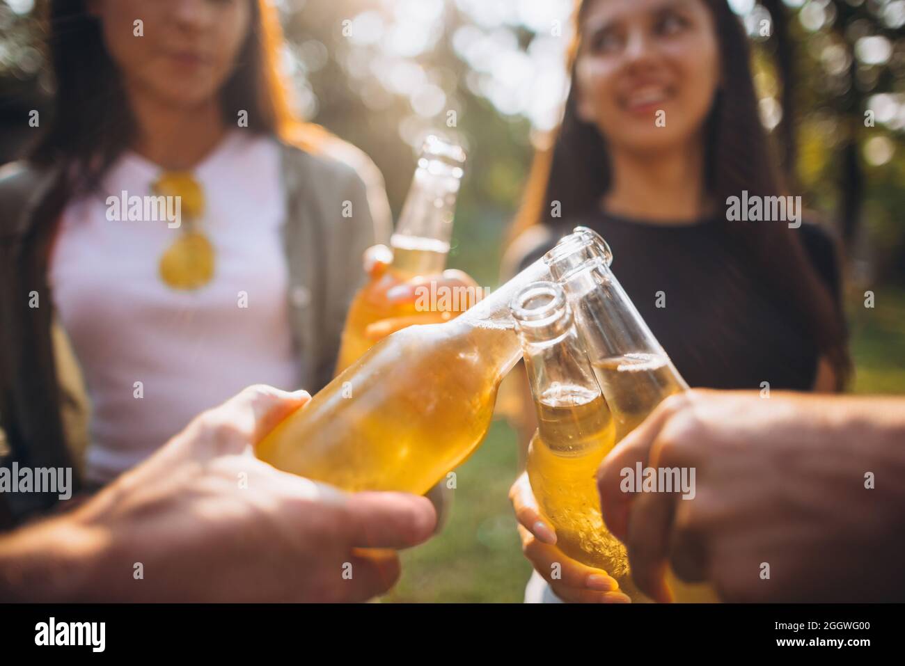 Close-up image of cropped hands holding beer bottles clinking. Cheers ...