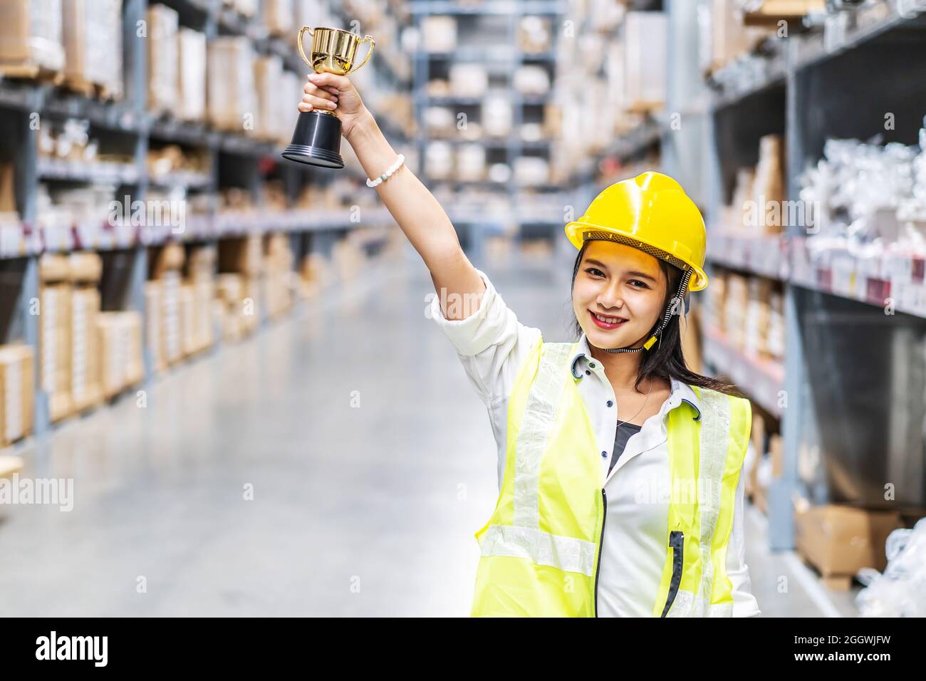 Happy woman warehouse worker holding a trophy after being select Stock ...