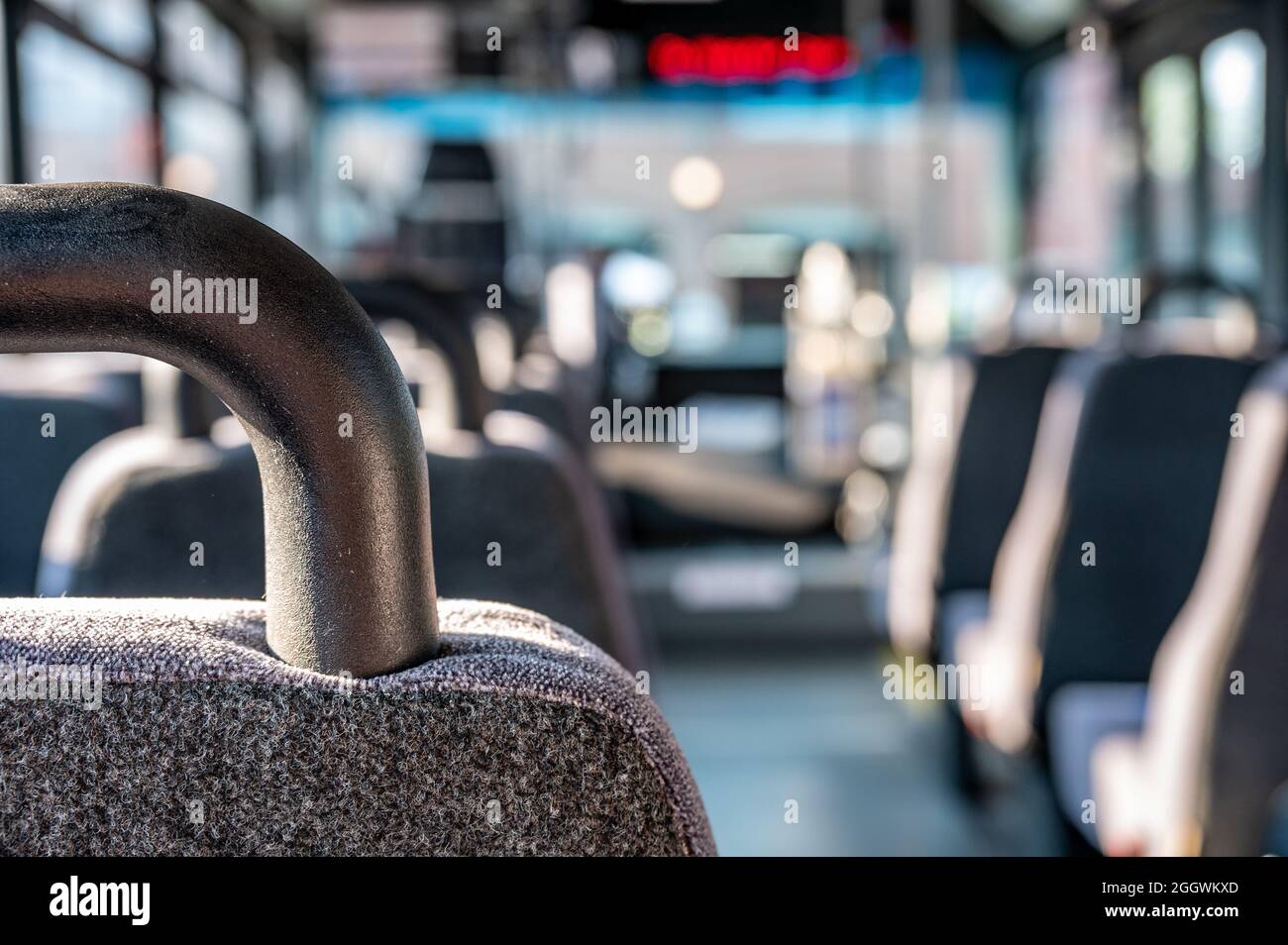 Focus on headrest of empty metro bus with the aisle to the front ...