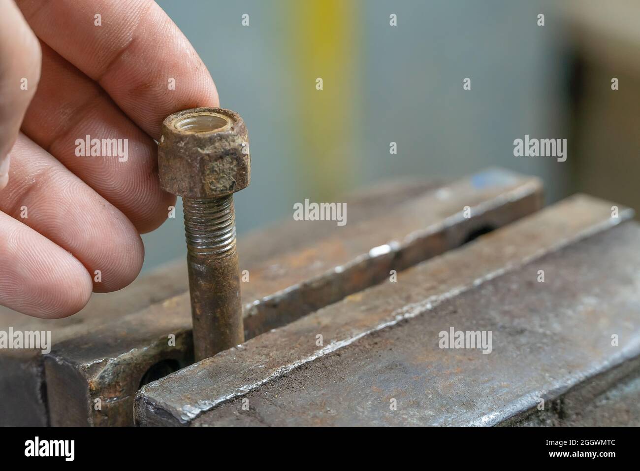 Close-up of a man's hand inserting a bolt into a metal clip in a garage ...