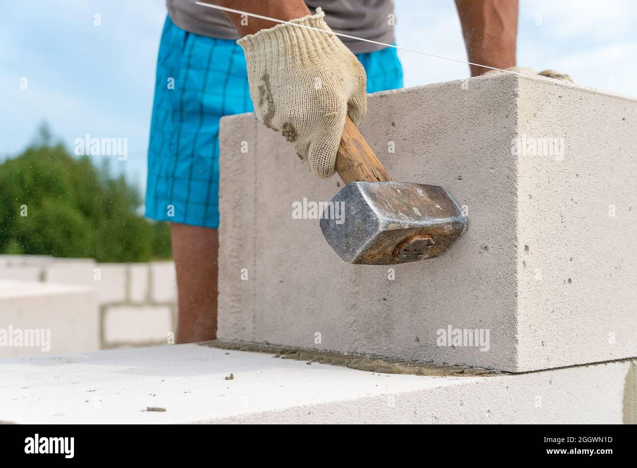 Builder uses a hammer to tamp aerated concrete blocks on the ...