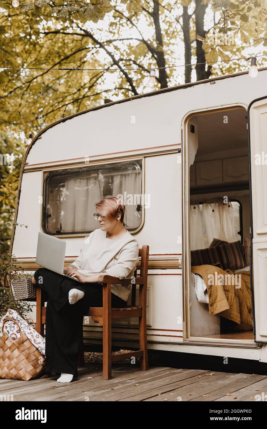 Woman sitting near motorhome RV and working on laptop Stock Photo - Alamy