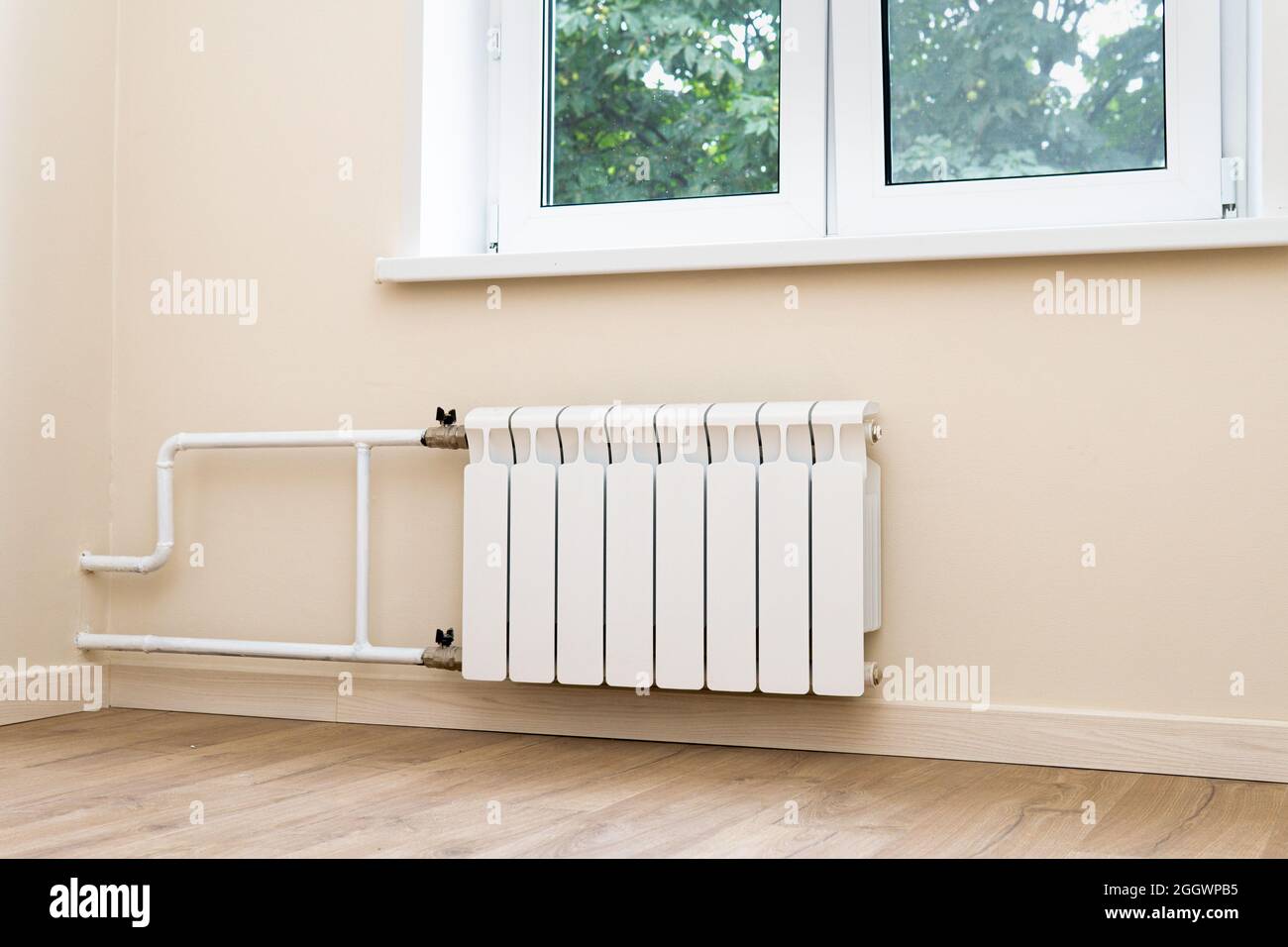 Modern water heating radiator attached to the wall under the window ...