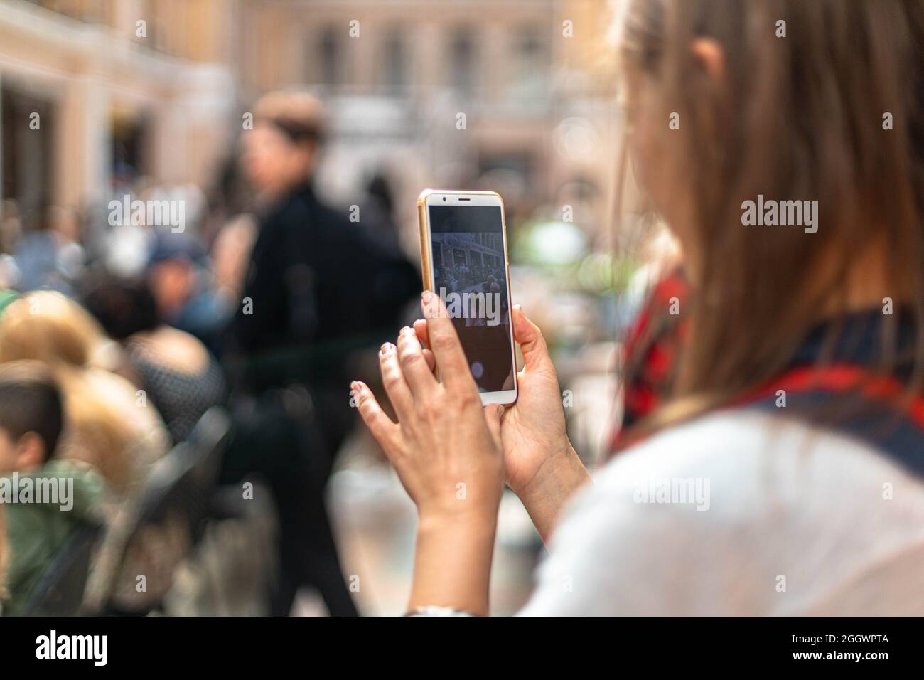 Woman taking pictures using smartphone or filming video of models on ...