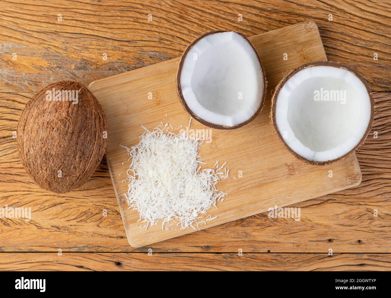 Coconuts with open fruit and coconut flakes over wooden table Stock ...