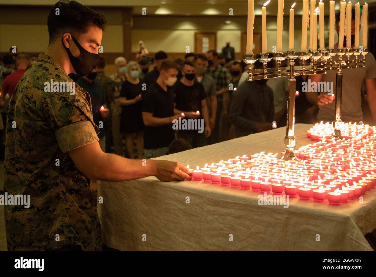 A U.S. Marine assigned to Marine Corps Base Hawaii sets a lit candle on ...