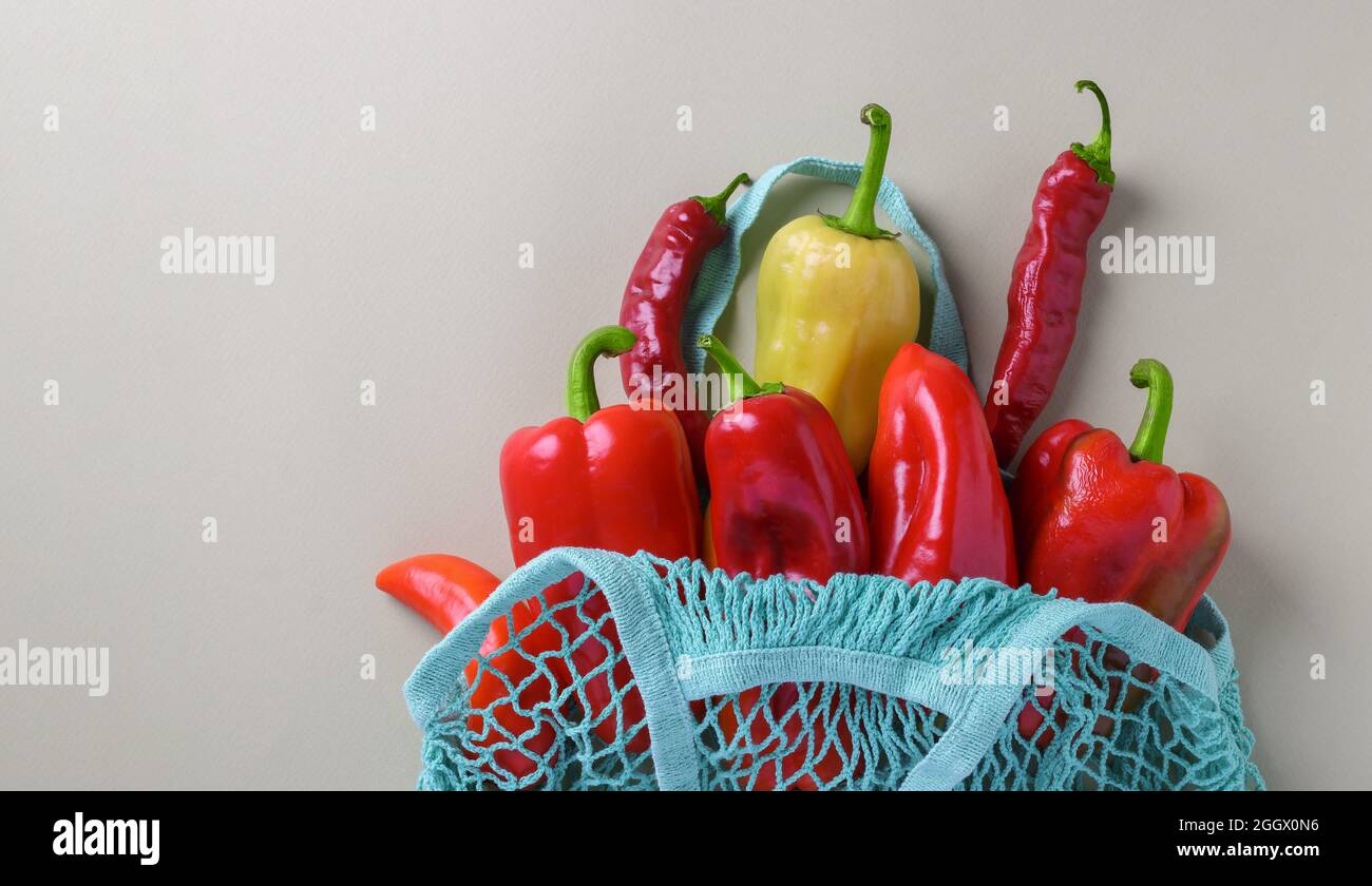 Zero waste concept. Various colorful peppers in turquoise string mesh ...