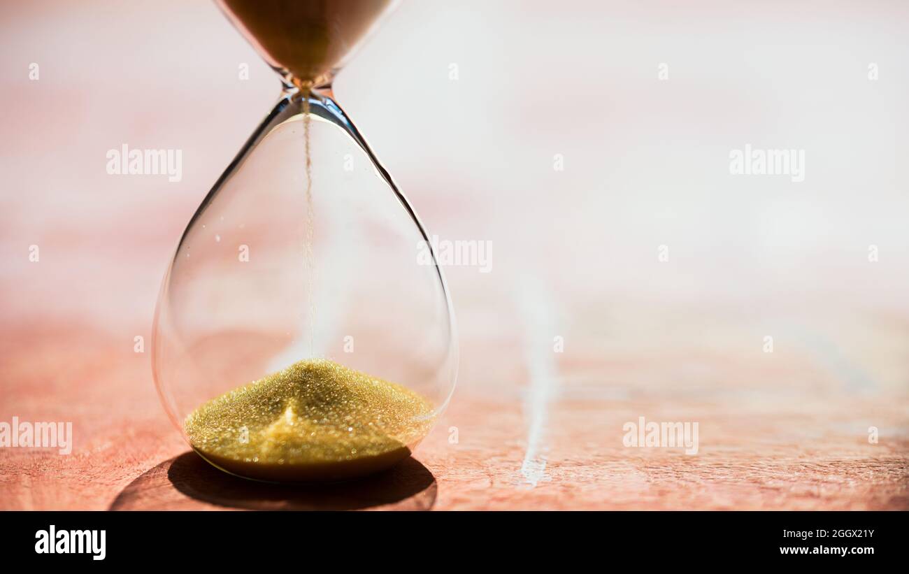Gold Sand running through the bulbs of an hourglass measuring the ...