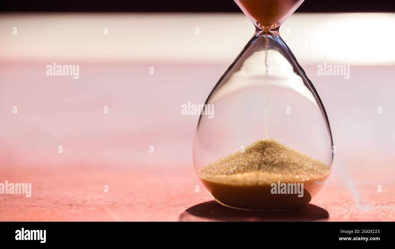 Gold Sand running through the bulbs of an hourglass measuring the ...