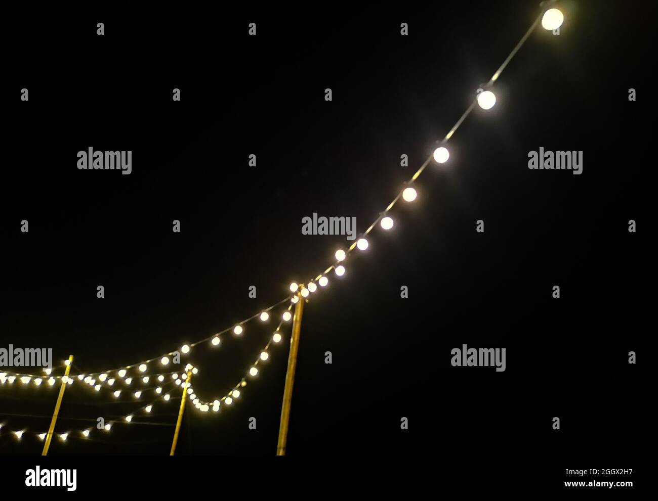 a many light bulb with wire cable at night time Stock Photo - Alamy