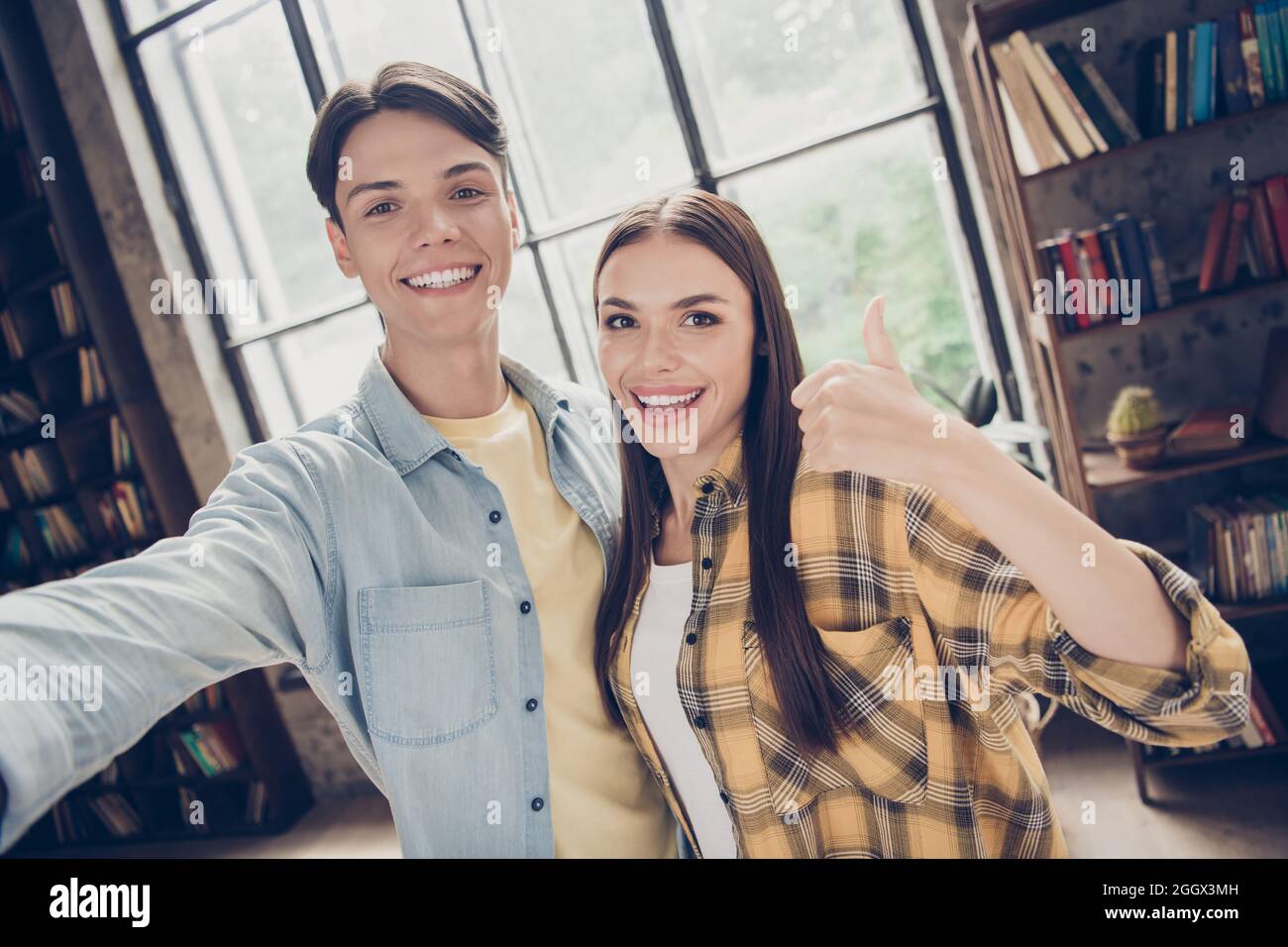 Self-portrait of two attractive cheerful people hugging showing thumbup ...