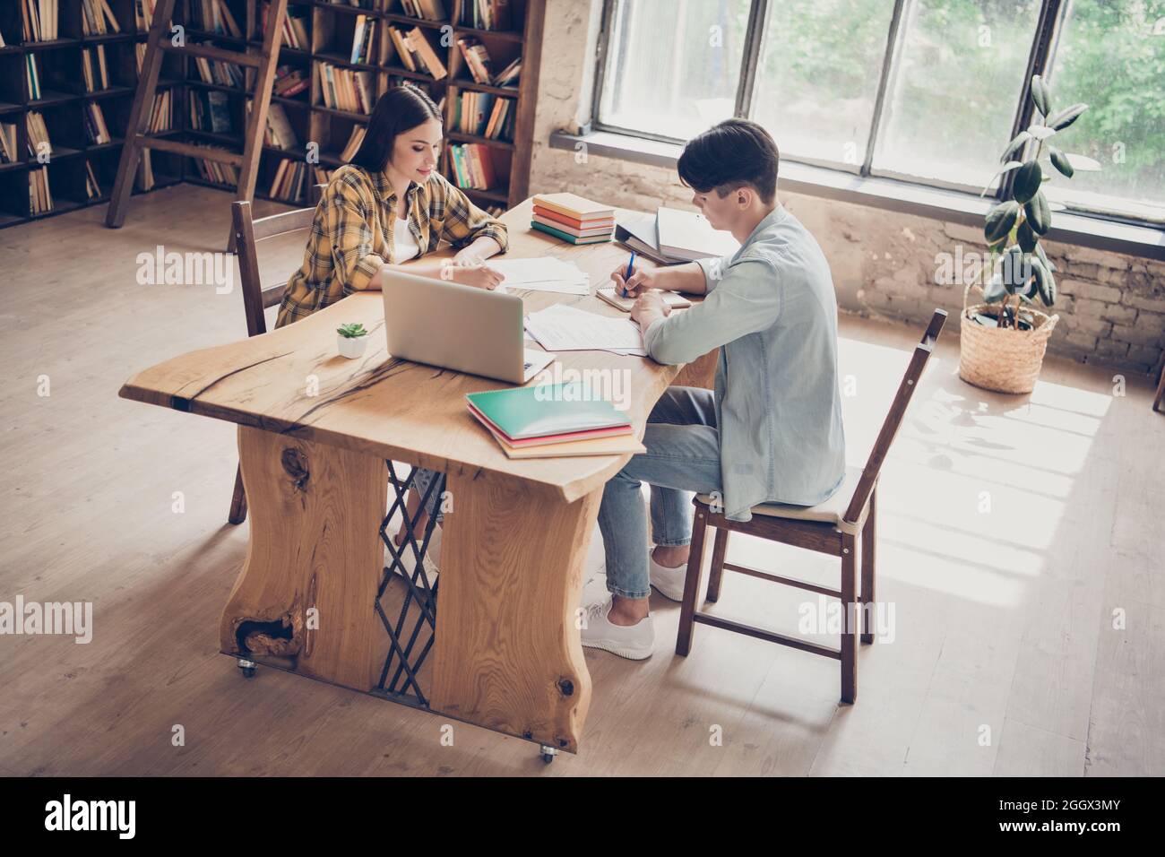 Portrait of two attractive focused busy people writing essay document ...
