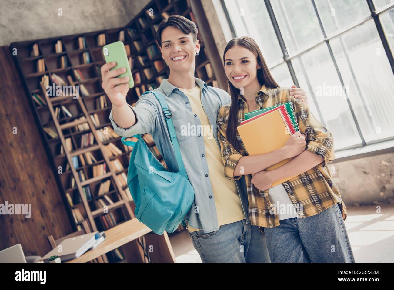 Portrait of two attractive cheerful friends friendship learners hugging ...
