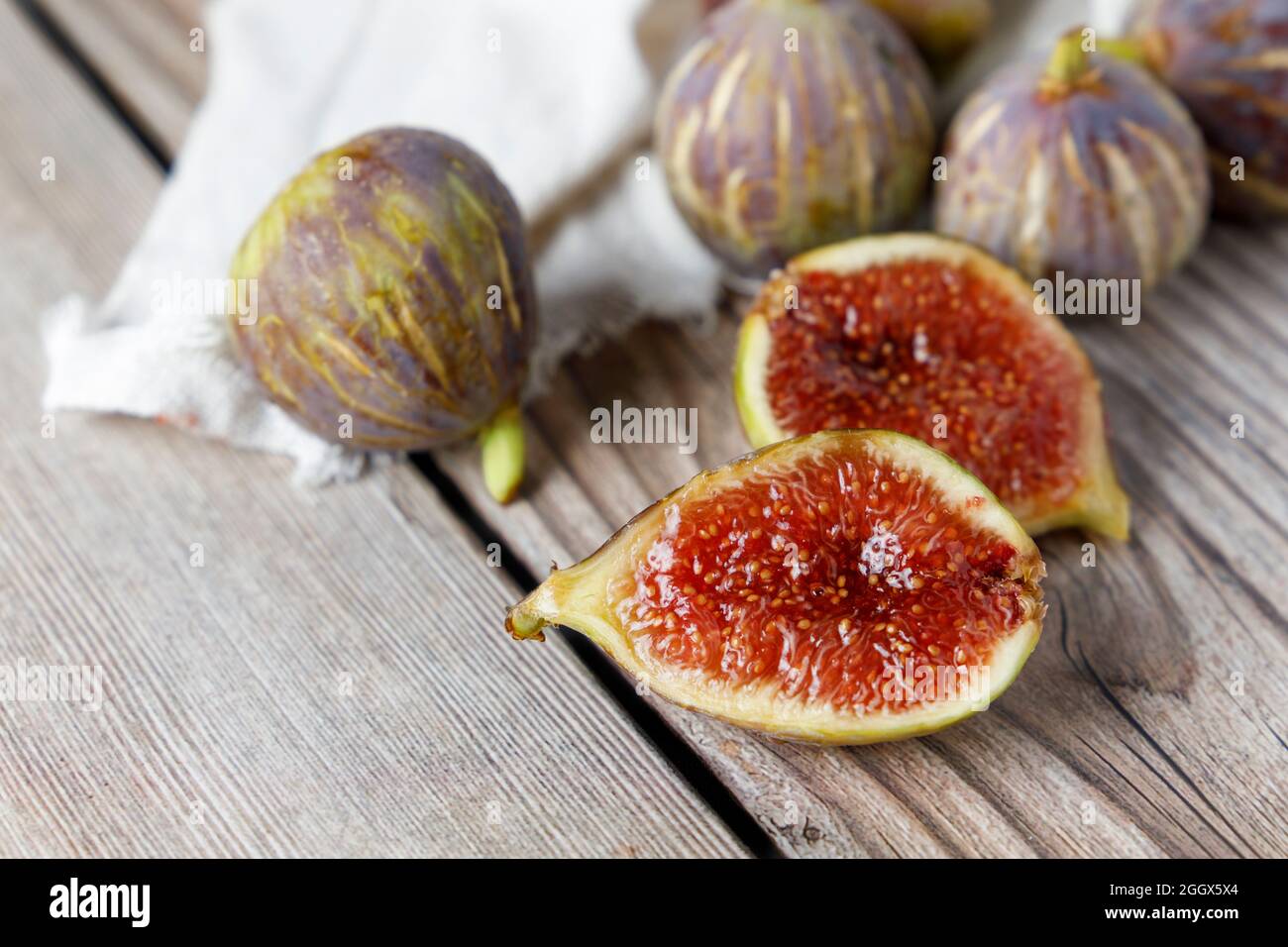 fig open in two parts next to other whole figs on wooden table Stock ...
