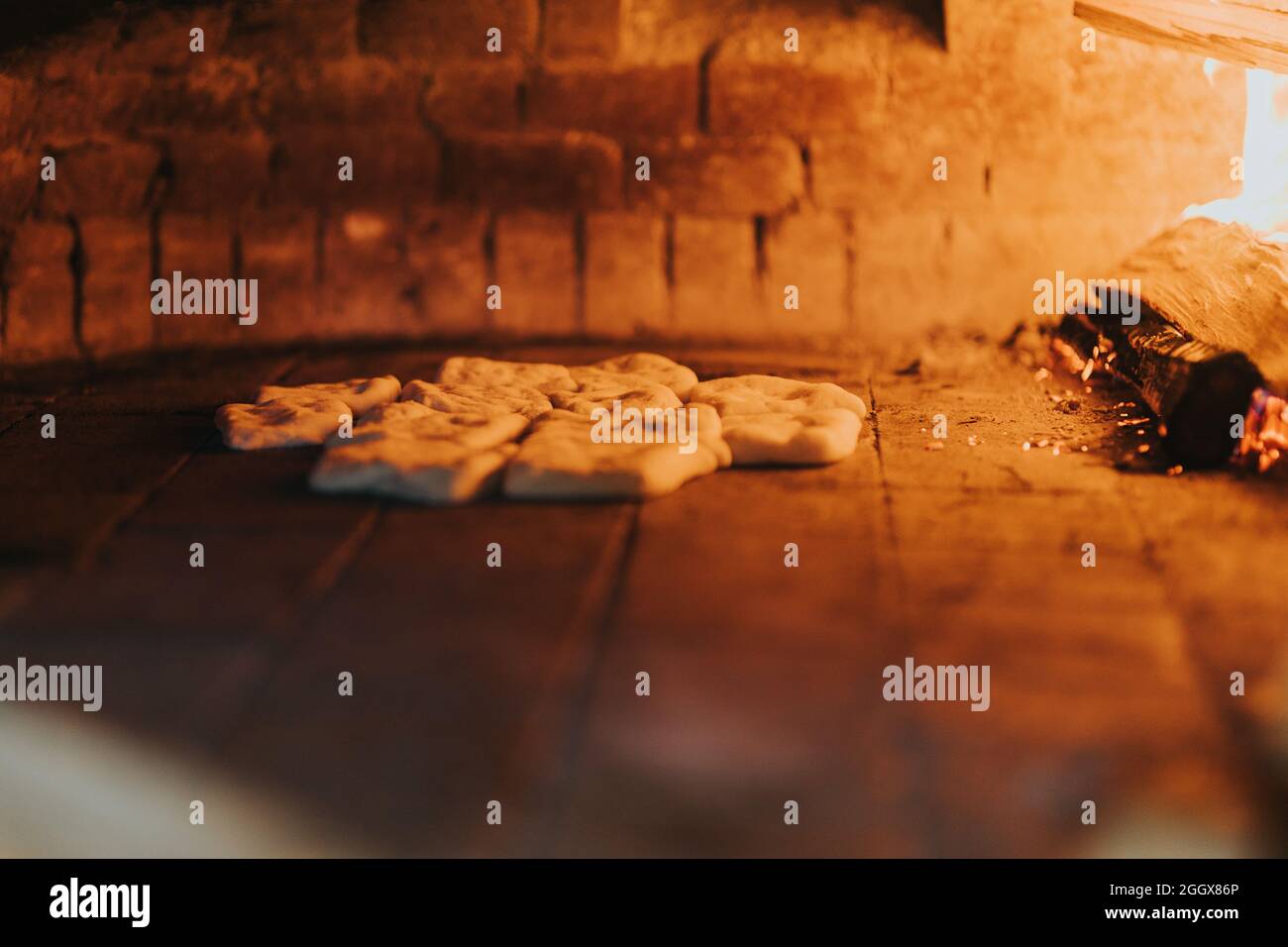 Closeup shot of pieces of bread baking in a stone oven with big fire ...
