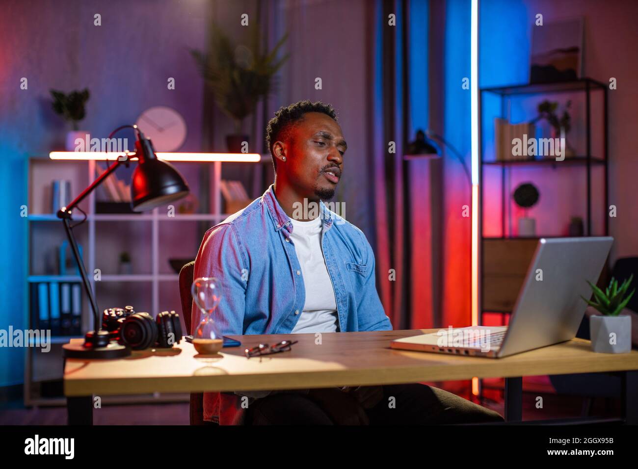 Young african man feeling bored, sad and tired while working on ...