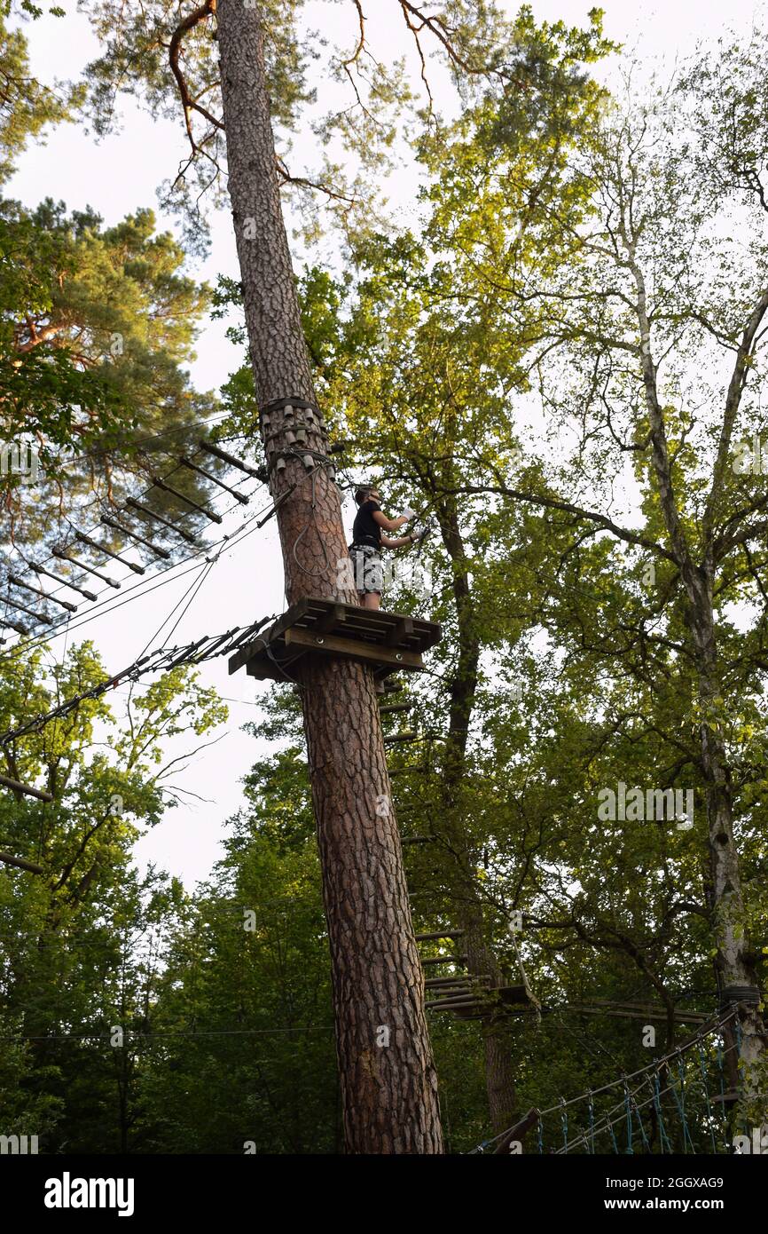 Young guy runs an obstacle course from tree to tree on a rope park ...