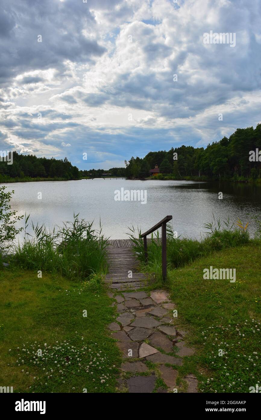 Small wooden pier with a railing on the shore of the lake and a stone ...