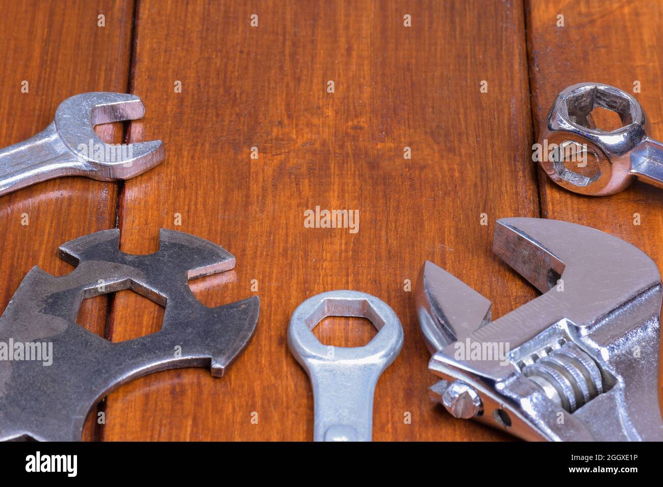Different types of wrenches lie on a wooden background spread out below ...