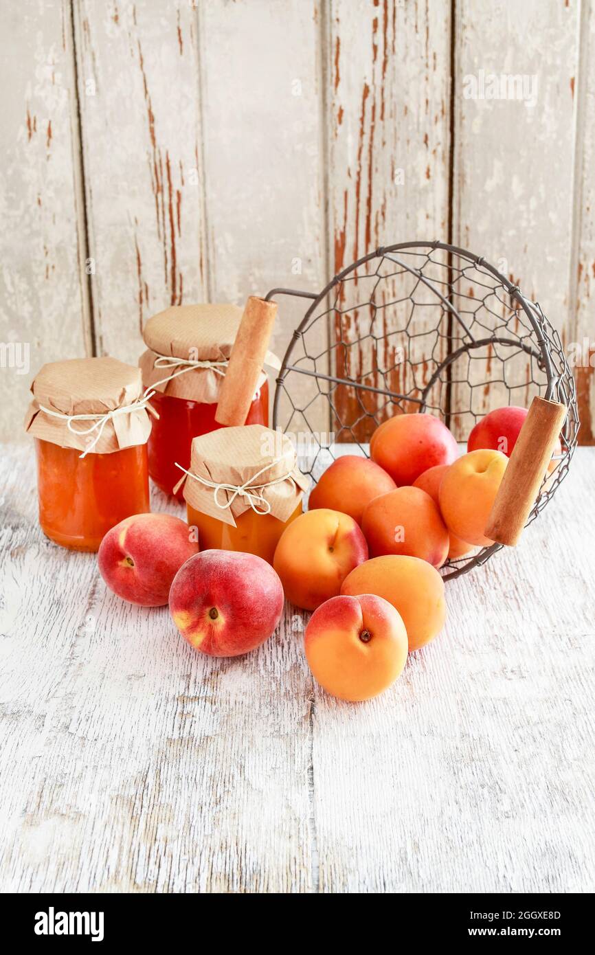 Two jars of jam and wire basket with ripe peaches. Healthy food Stock ...