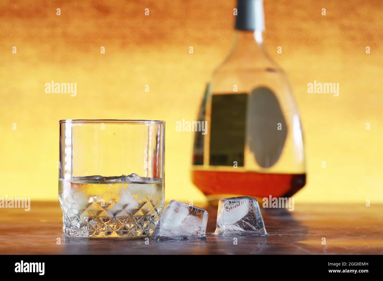 A glass of hard alcohol with ice on a bar counter. Whiskey with soda in ...