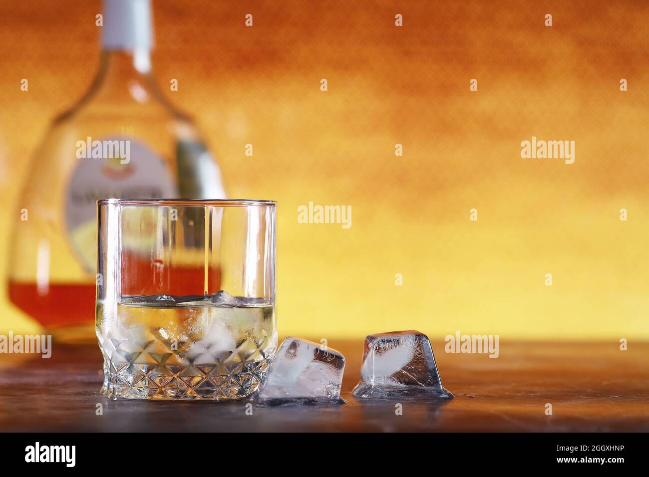 A glass of hard alcohol with ice on a bar counter. Whiskey with soda in ...