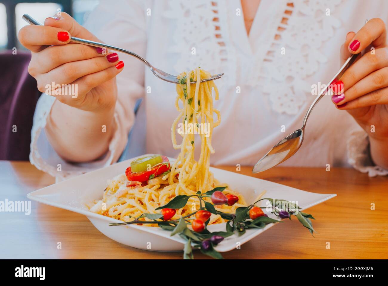 Closeup of a person eating pasta with herbs and garnish in a restaura ...
