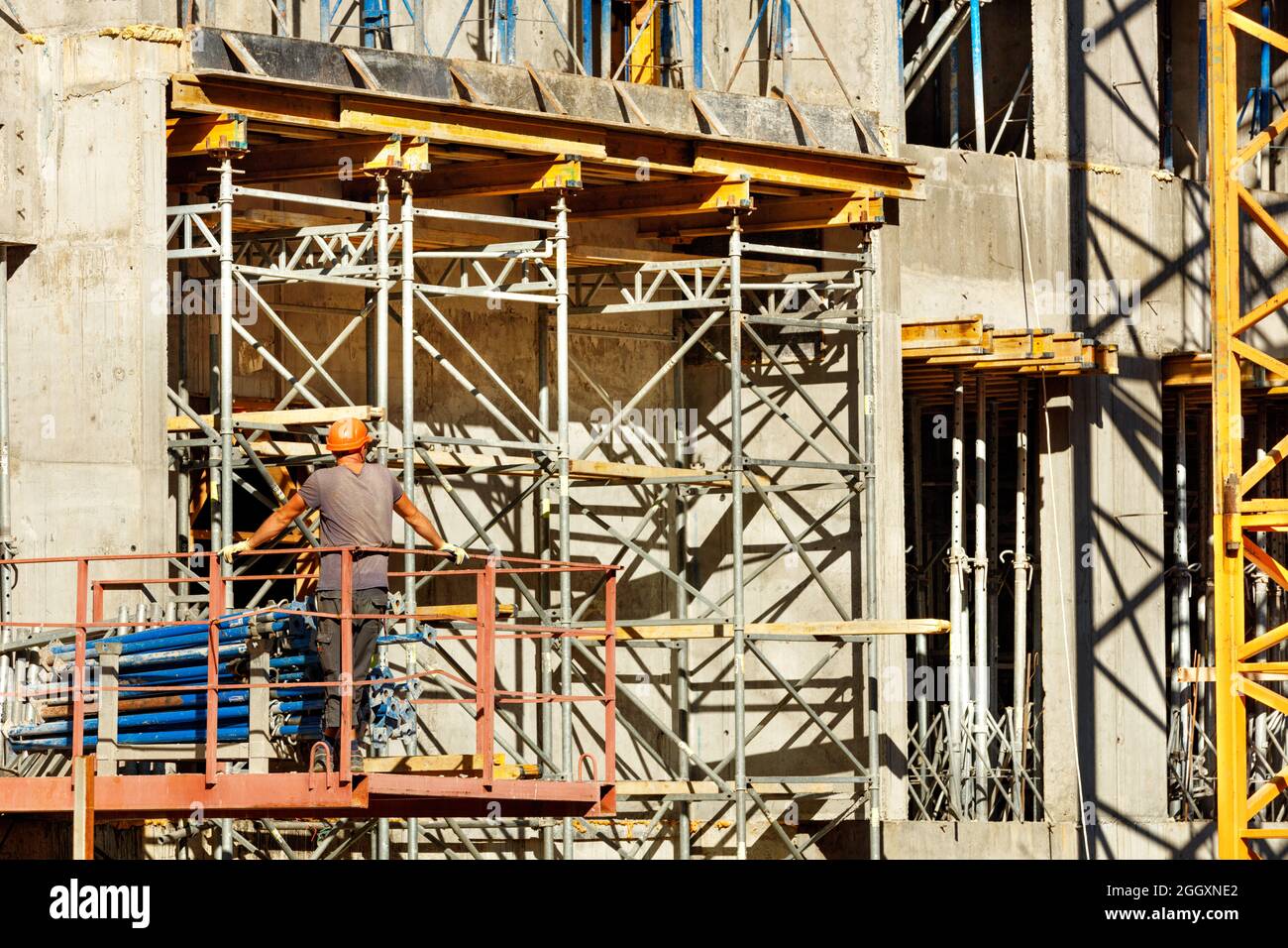 A builder installs a system of metal scaffolding and supports in a new ... A builder installs a system of metal scaffolding and supports in a new ...