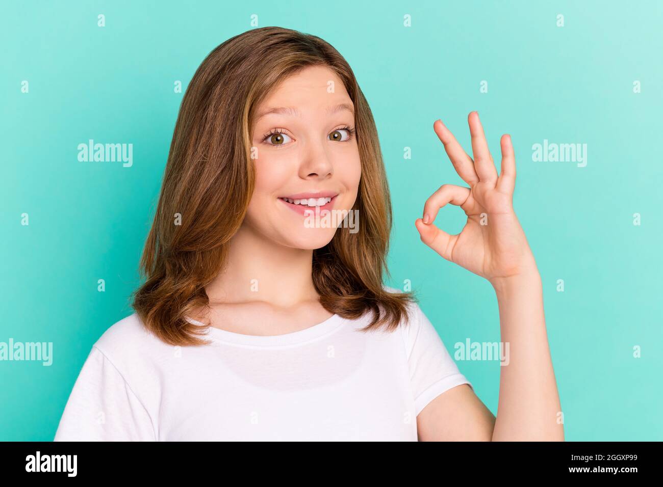 Photo portrait little girl smiling showing okay gesture in white t ...