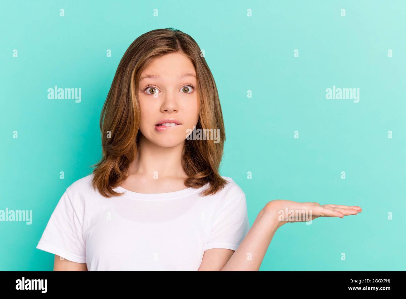 Photo portrait little girl biting lip keeping blank space on hand ...