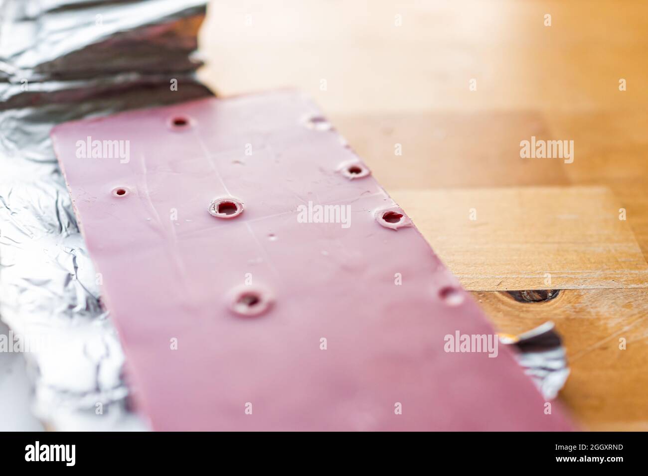 Closeup of pink trendy ruby chocolate bar on plate with aluminum foil ...