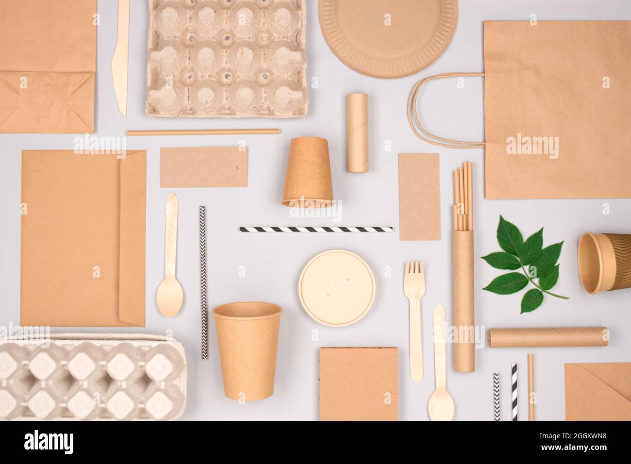 Different eco-friendly tableware and kraft paper food packaging on gray ...