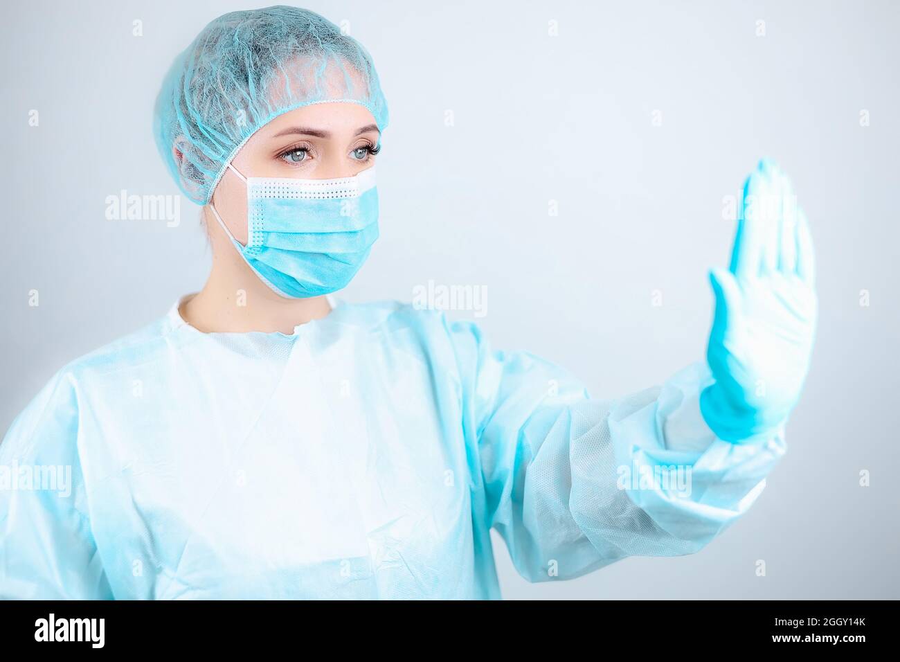 a nurse in a medical gown, mask, and protective gloves is standing ...