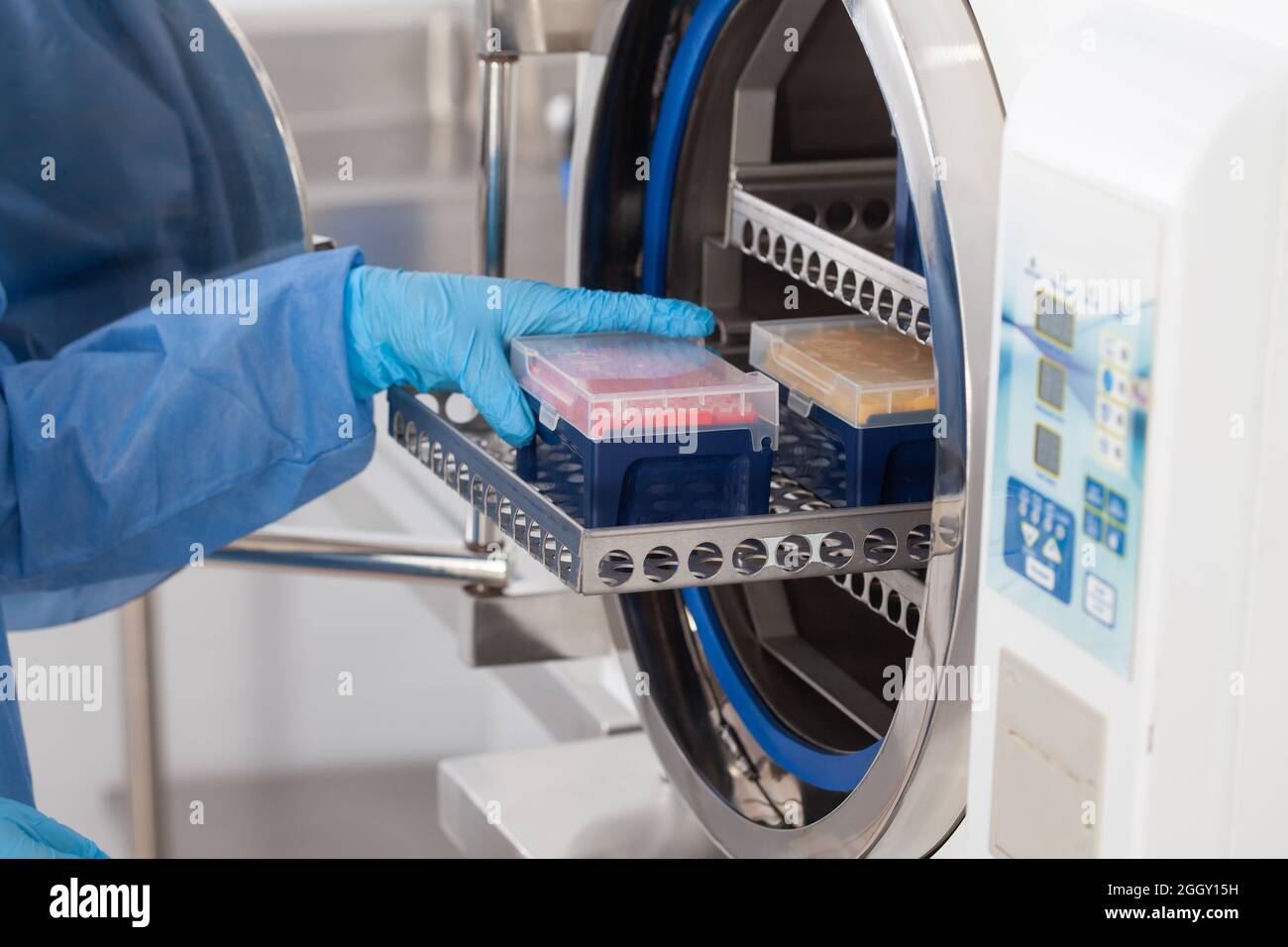 Young female scientist sterilizing laboratory material in autoclave ...