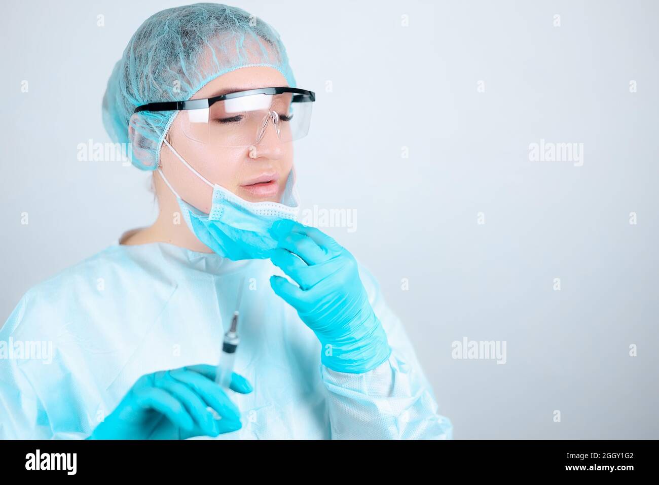 A nurse in a medical gown, mask and protective gloves with transparent ...