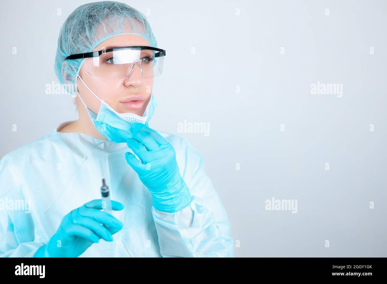 A nurse in a medical gown, mask and protective gloves with transparent ...