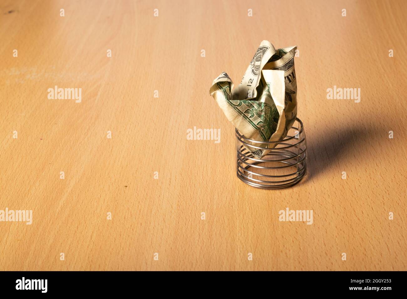 Crumpled dollar bill on compressed steel spring about to release Stock ...