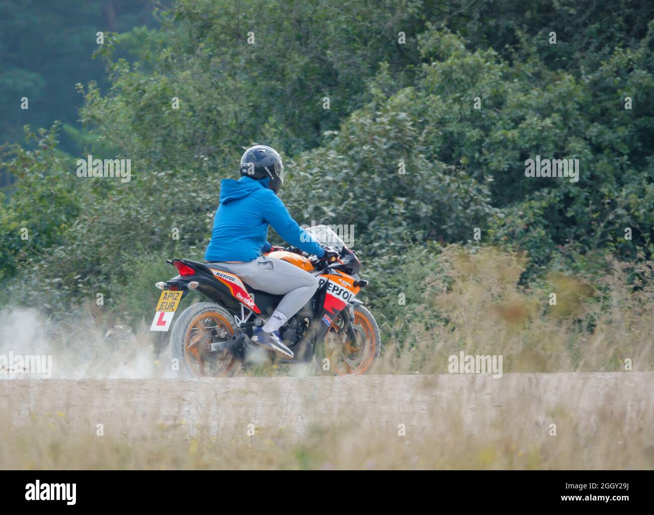 Learner motor cyclist travelling a dust track on his Repsol liveried ...