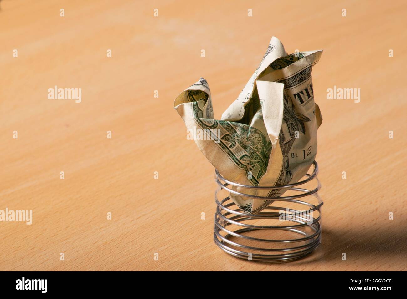 Crumpled dollar bill on compressed steel spring about to release Stock ...