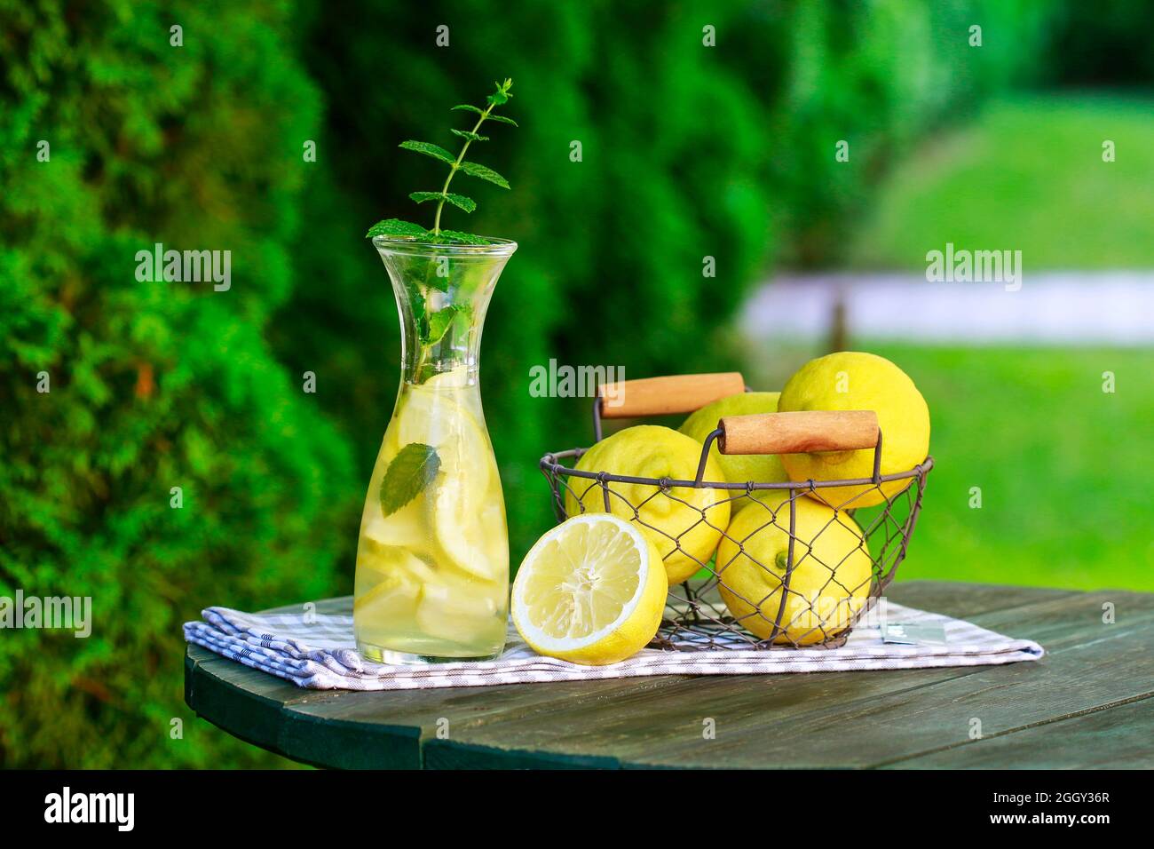 Lemonade in the bottle and fresh fruits in wire basket. Summer garden ...