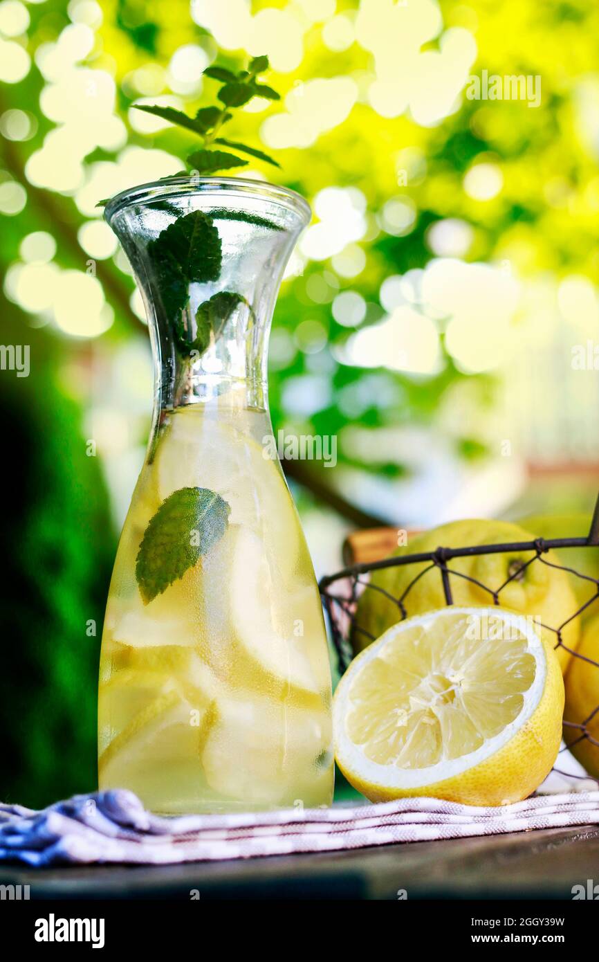 Lemonade in the bottle and fresh fruits in wire basket. Summer garden ...