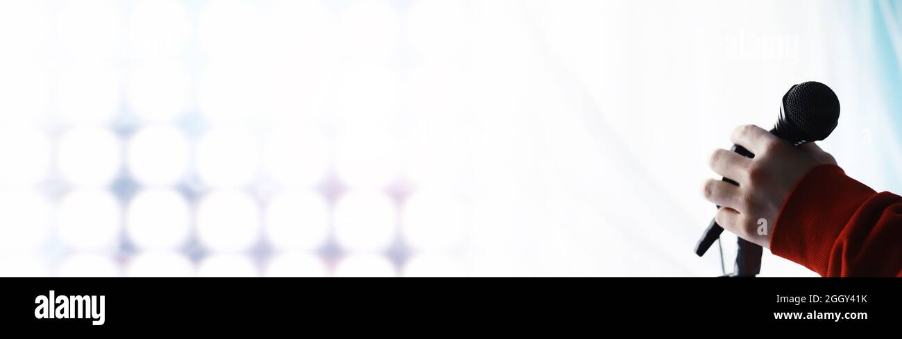 Stand with a microphone. Man holds hands a microphone on tripod ...